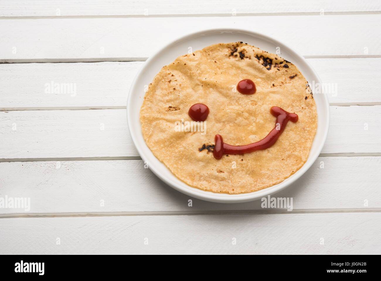 ketchup or fruit jelly/jam smile emoticon over indian bread / chapati ...