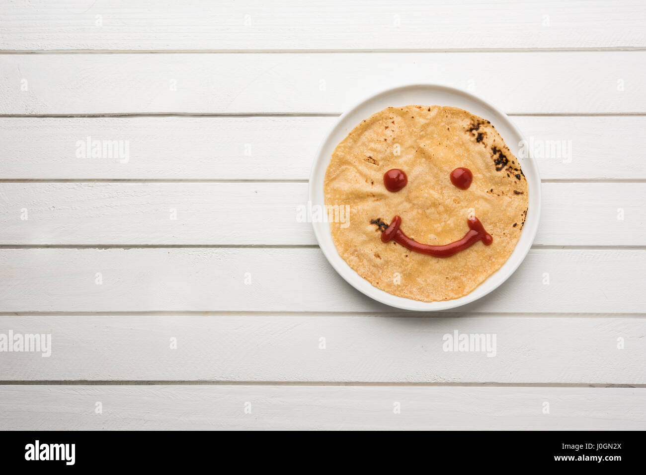 ketchup or fruit jelly/jam smile emoticon over indian bread / chapati ...