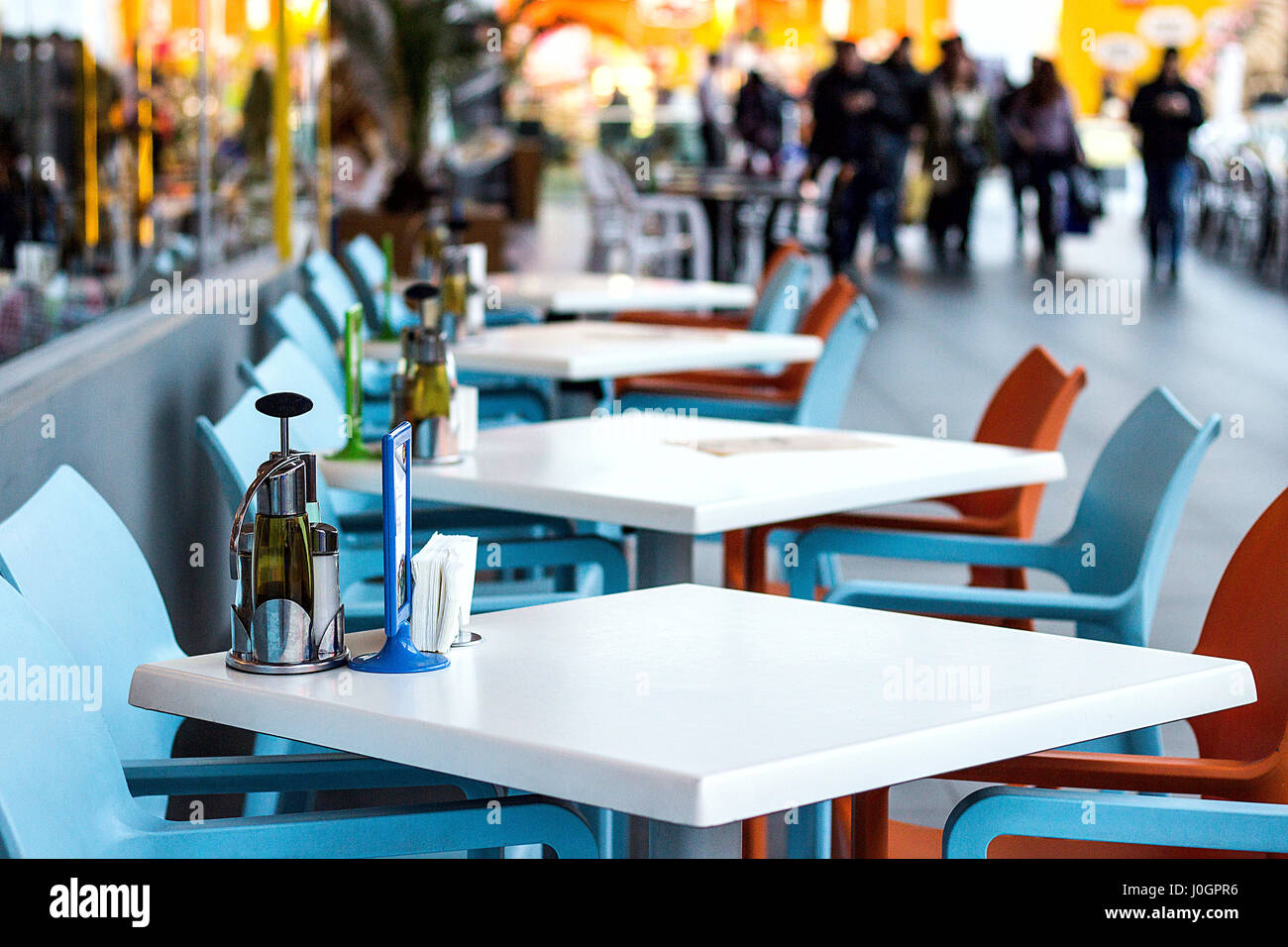 Empty tables at an outdoor cafe people pass by Stock Photo - Alamy