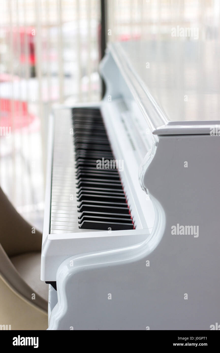 White piano with black keys near the window Stock Photo - Alamy
