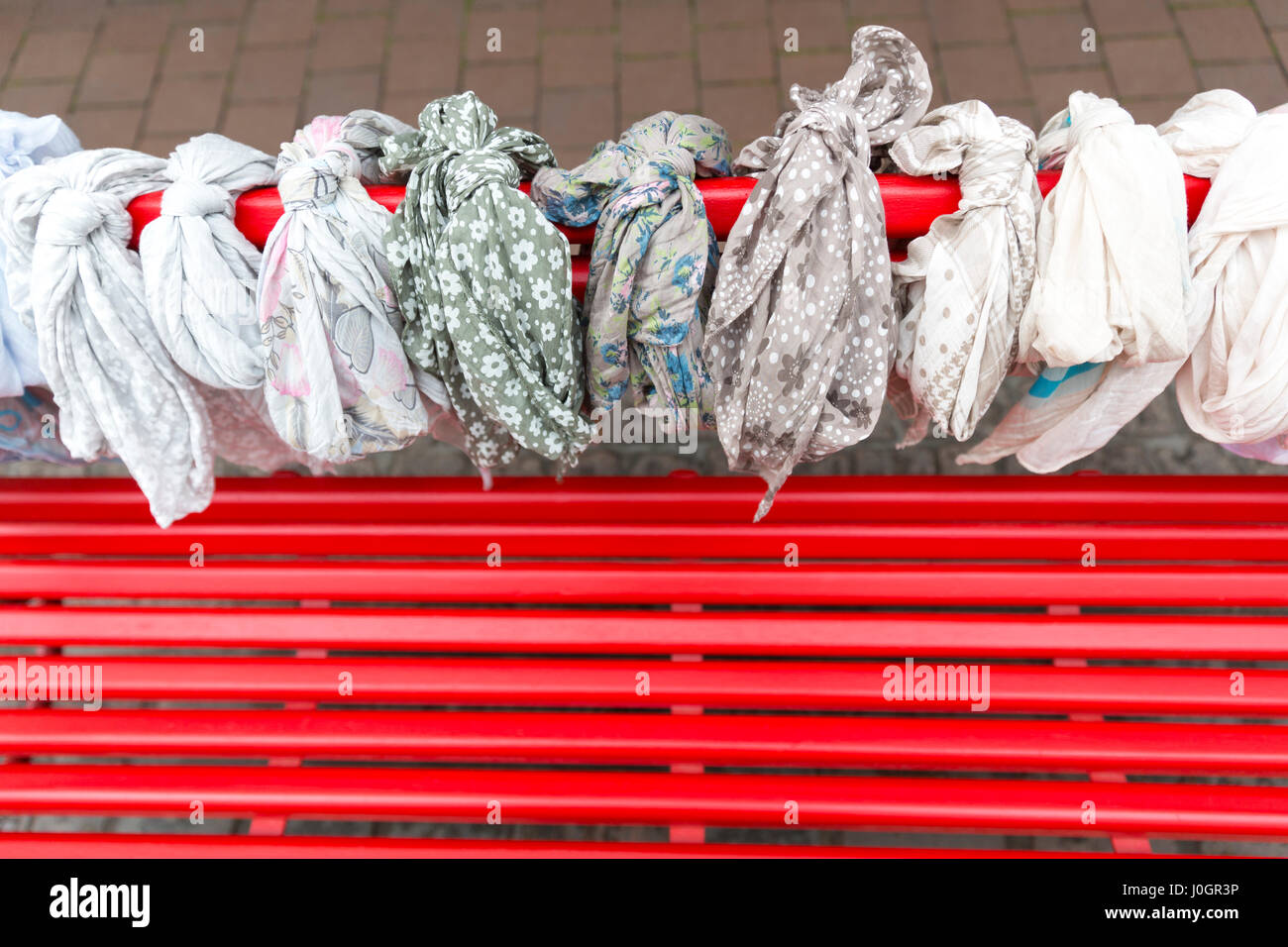 Display of women's scarves each scarf tied on brightly coloured bench ...