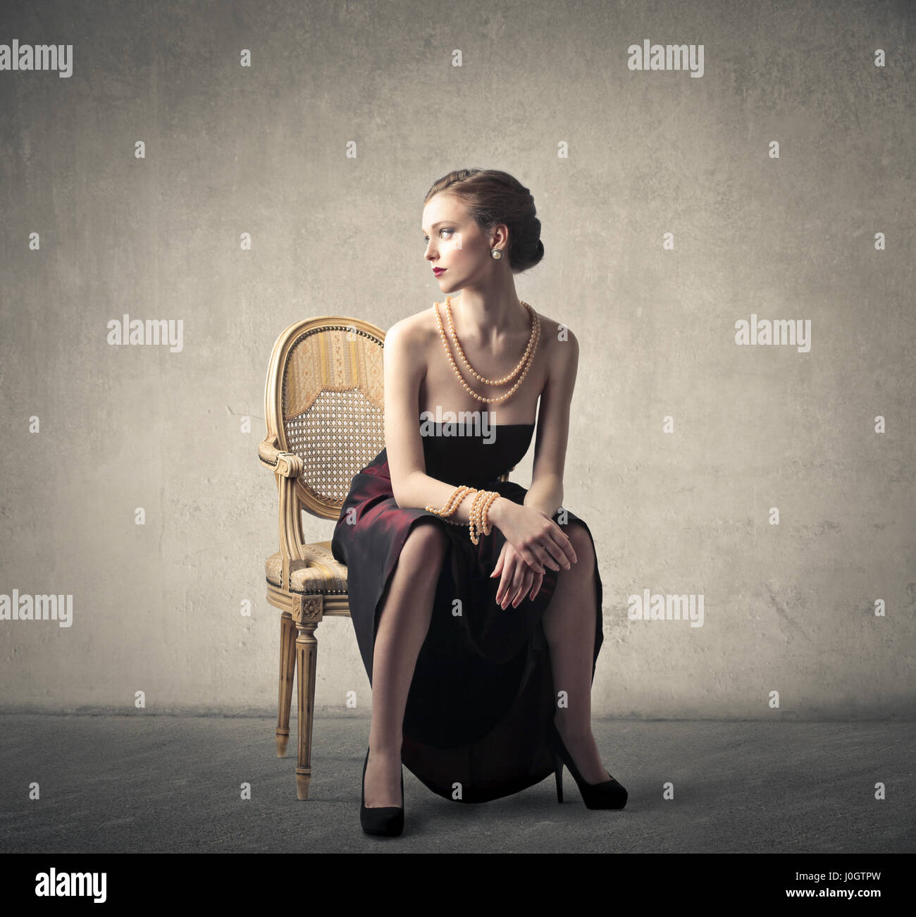 Elegant woman sitting on chair Stock Photo - Alamy