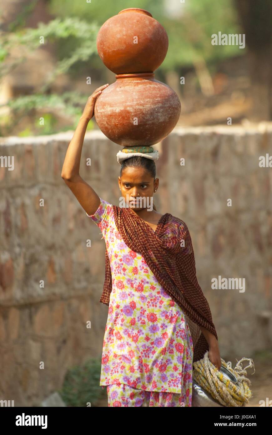 Young Woman Carrying Ceramic Pots On Their Head In Rajasthan India
