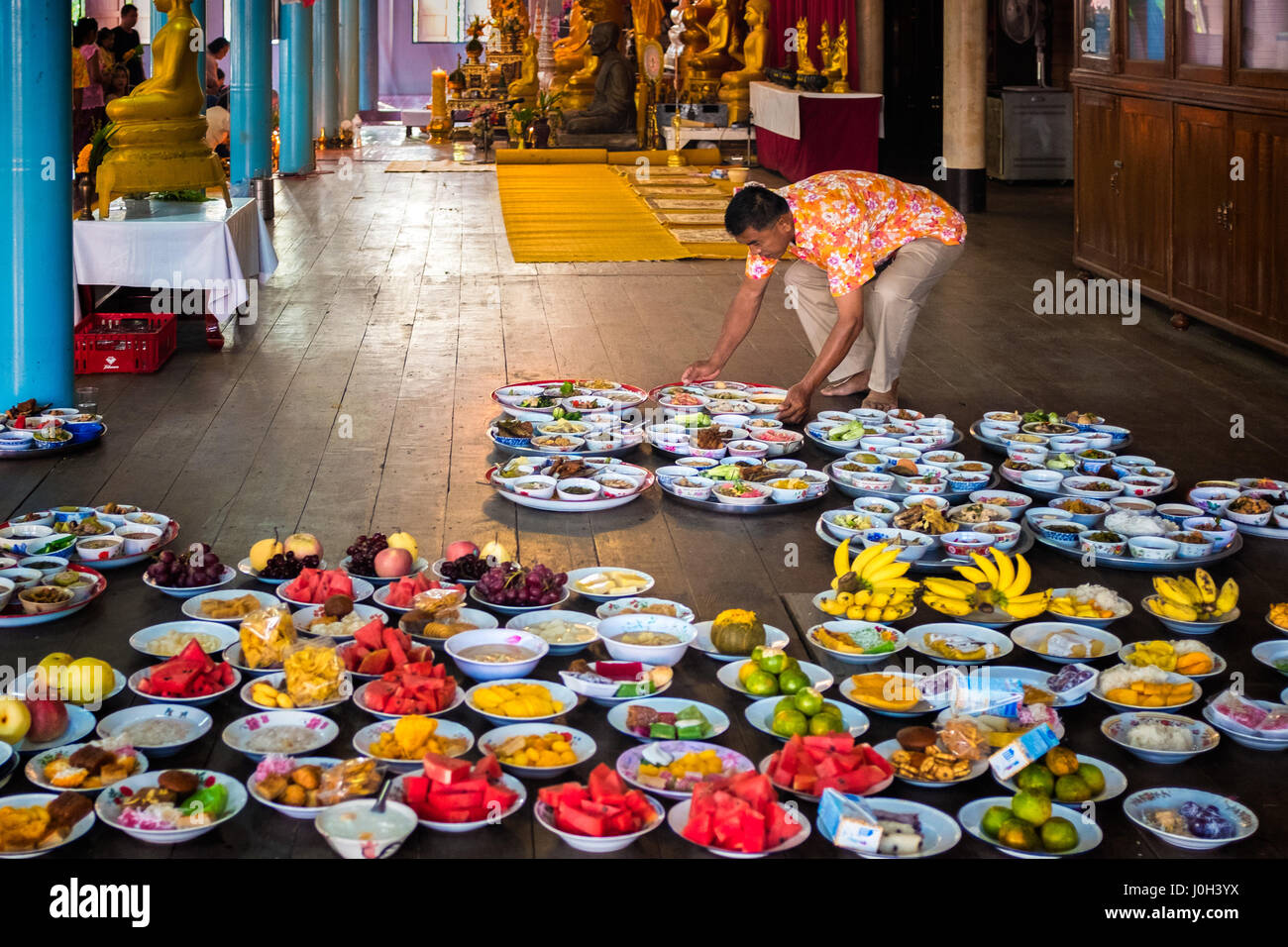 A local man loads food trays that will presented to the monks for ...