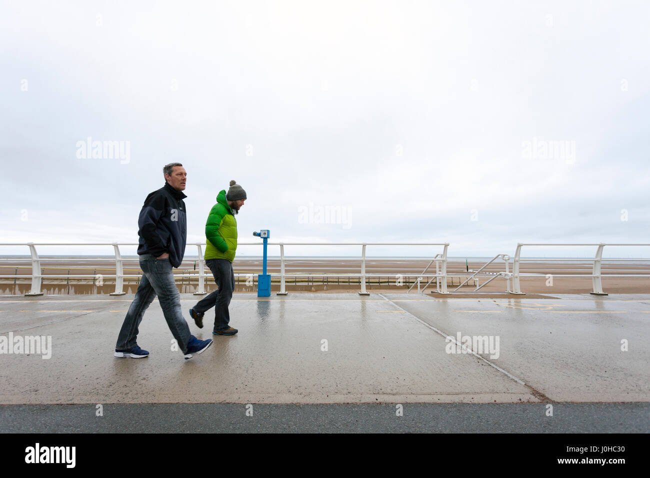 People walking along a wet and windy promenade at the popular tourist ...