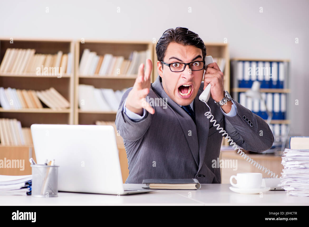 Angry businessman with too much work in office Stock Photo - Alamy