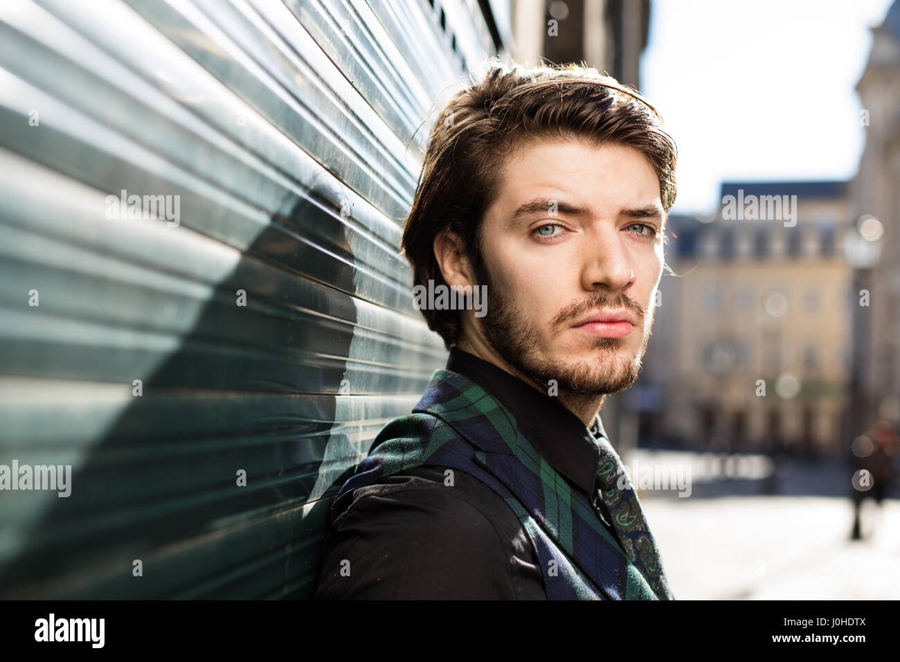 clouse up portrait of an elegant man standing outside next to a green ...