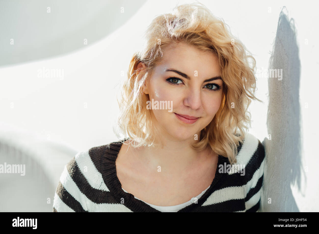 clouse up of a curly blonde woman standing outside and leaning on a ...