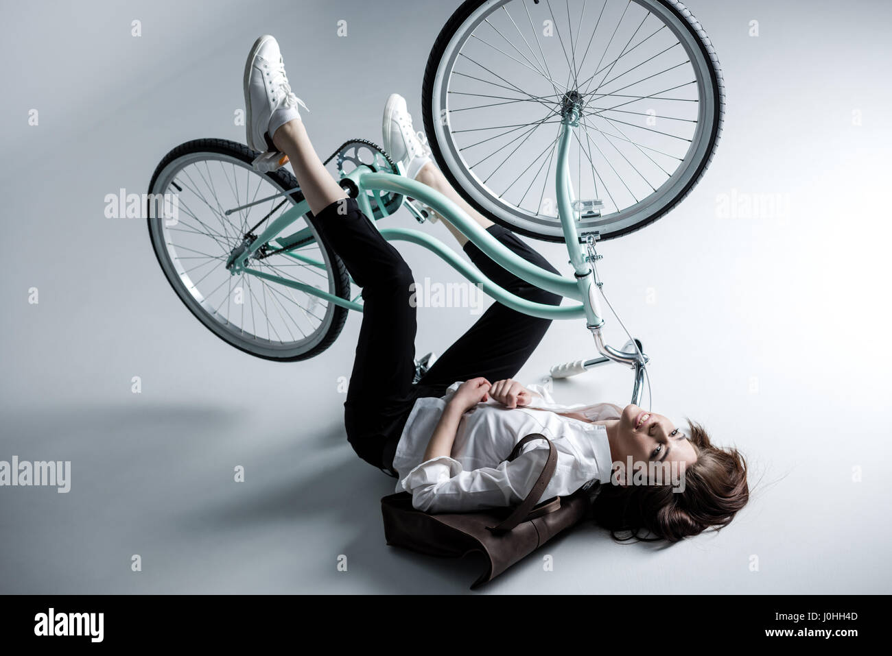 Stylish young beautiful woman lying with bicycle Stock Photo - Alamy