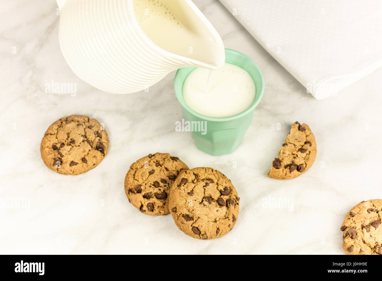 Milk poured into glass, with chocolate chips cookies Stock Photo - Alamy