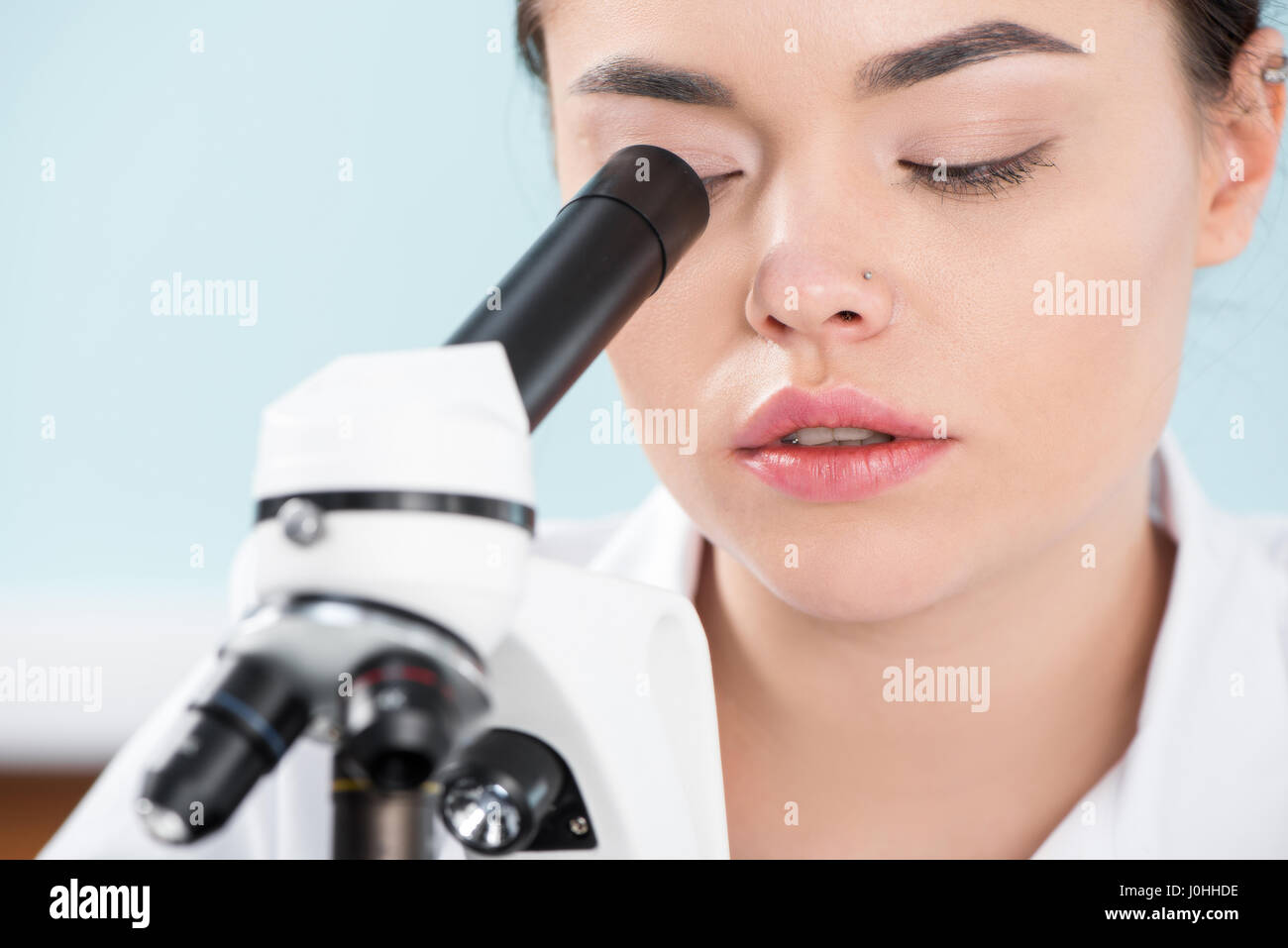 Close-up view of young female scientist looking in microscope Stock ...