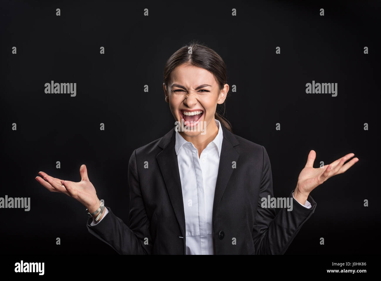 Attractive young businesswoman screaming at camera on black Stock Photo ...