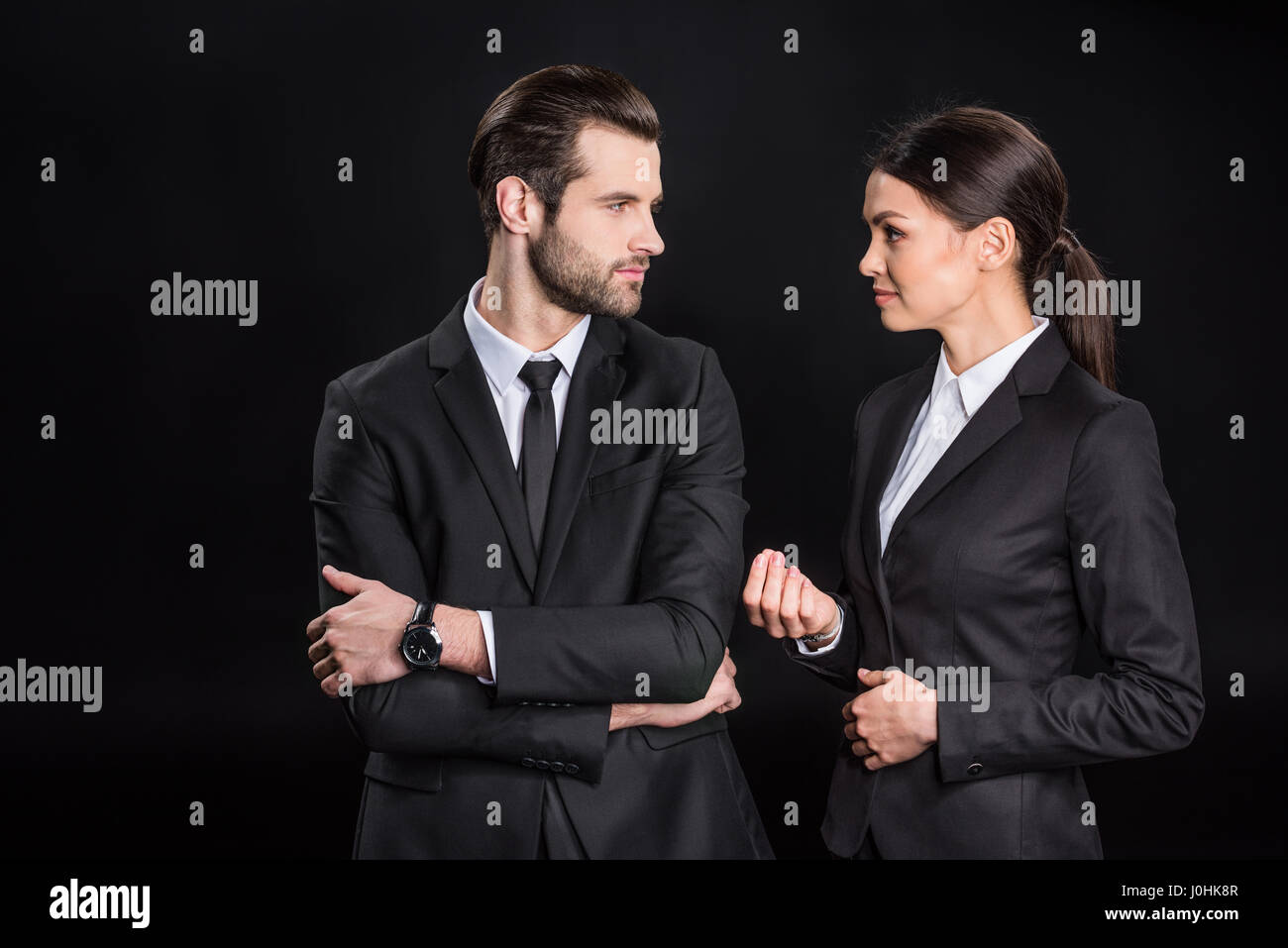 Young confident businesspeople in formal wear looking at each other on ...