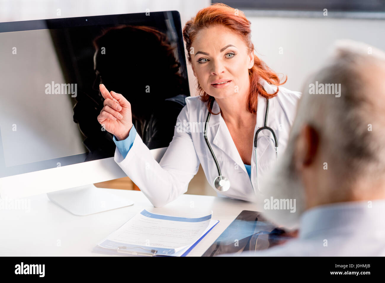 Female doctor pointing with finger on desktop computer and looking at ...