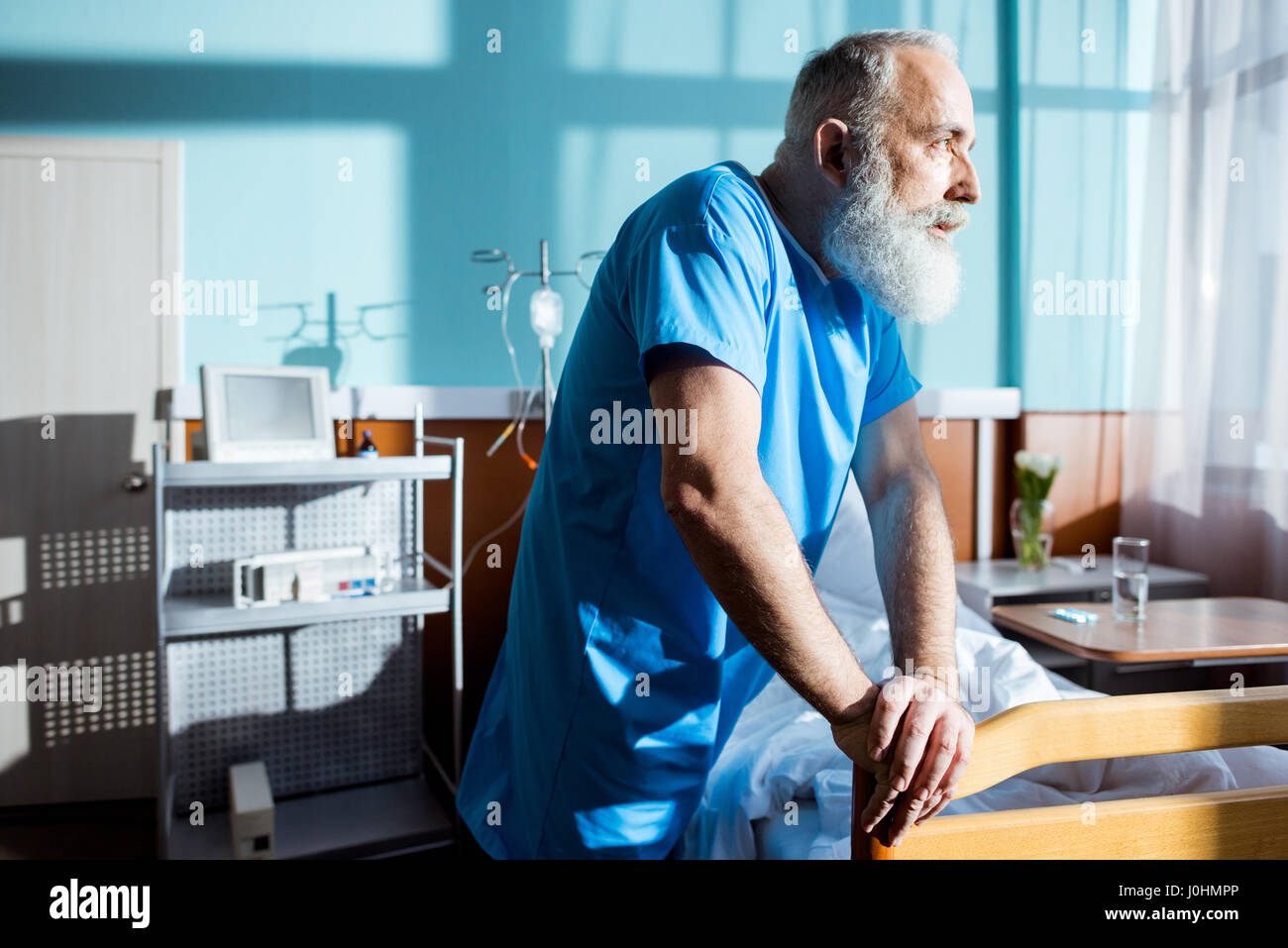 Side view of sick senior man standing in hospital room Stock Photo - Alamy