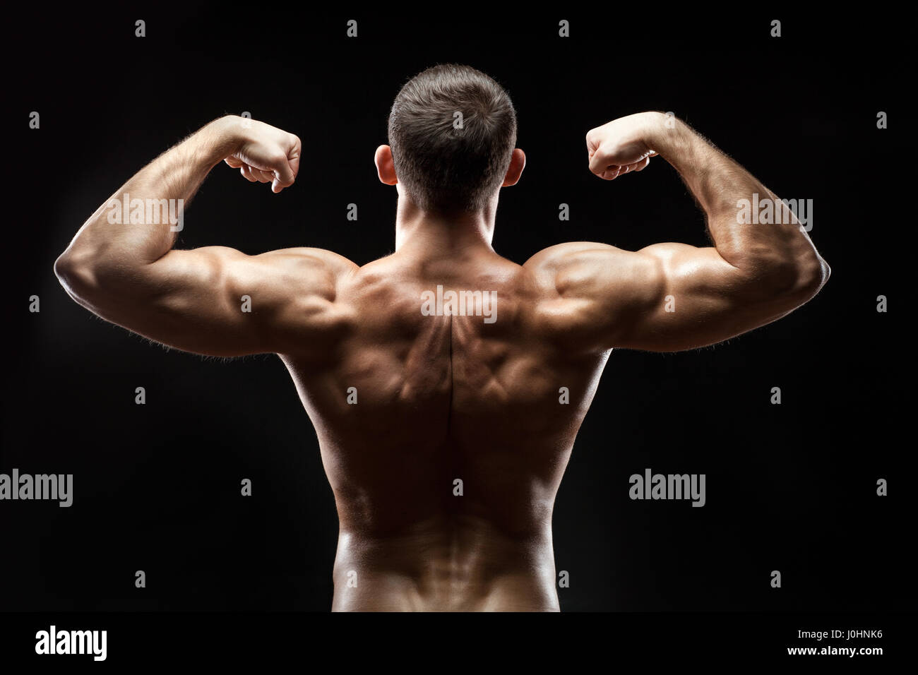 The man is standing back and showing big muscles on his back, he's on a ...