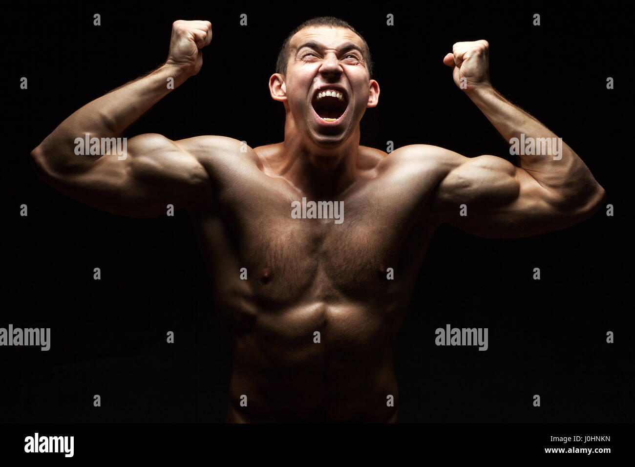Portrait of screaming bodybuilder with tight muscles and his mouth open ...