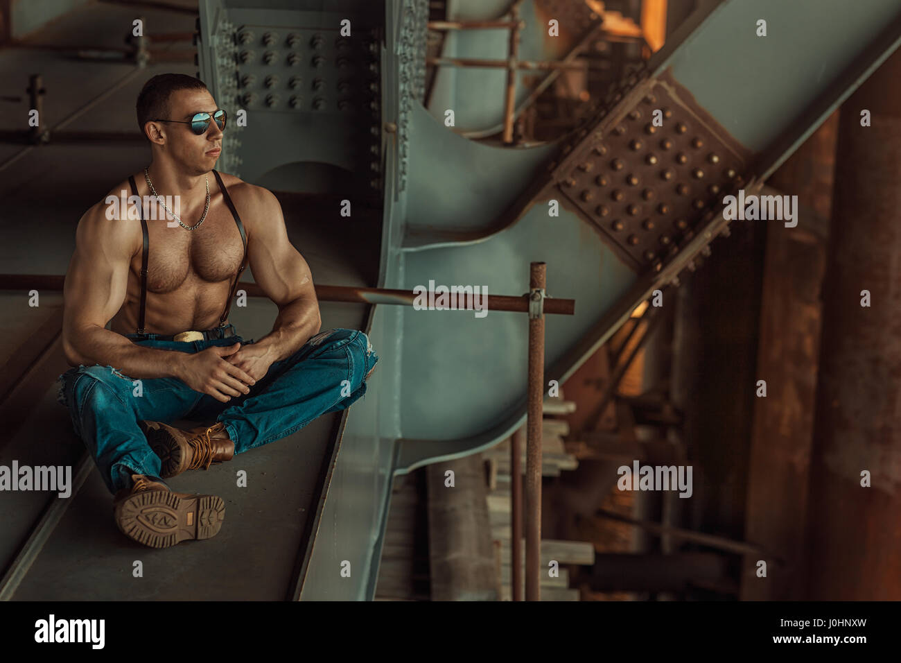 Muscular guy with glasses sitting on the edge of a high bridge Stock ...