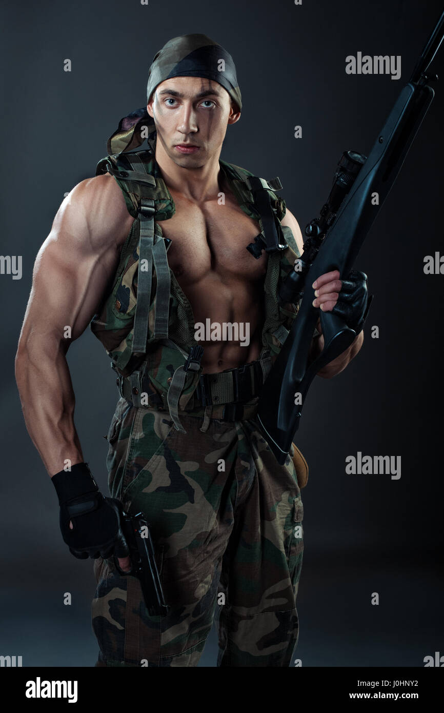 Man with large muscles in military uniform with weapon Stock Photo - Alamy