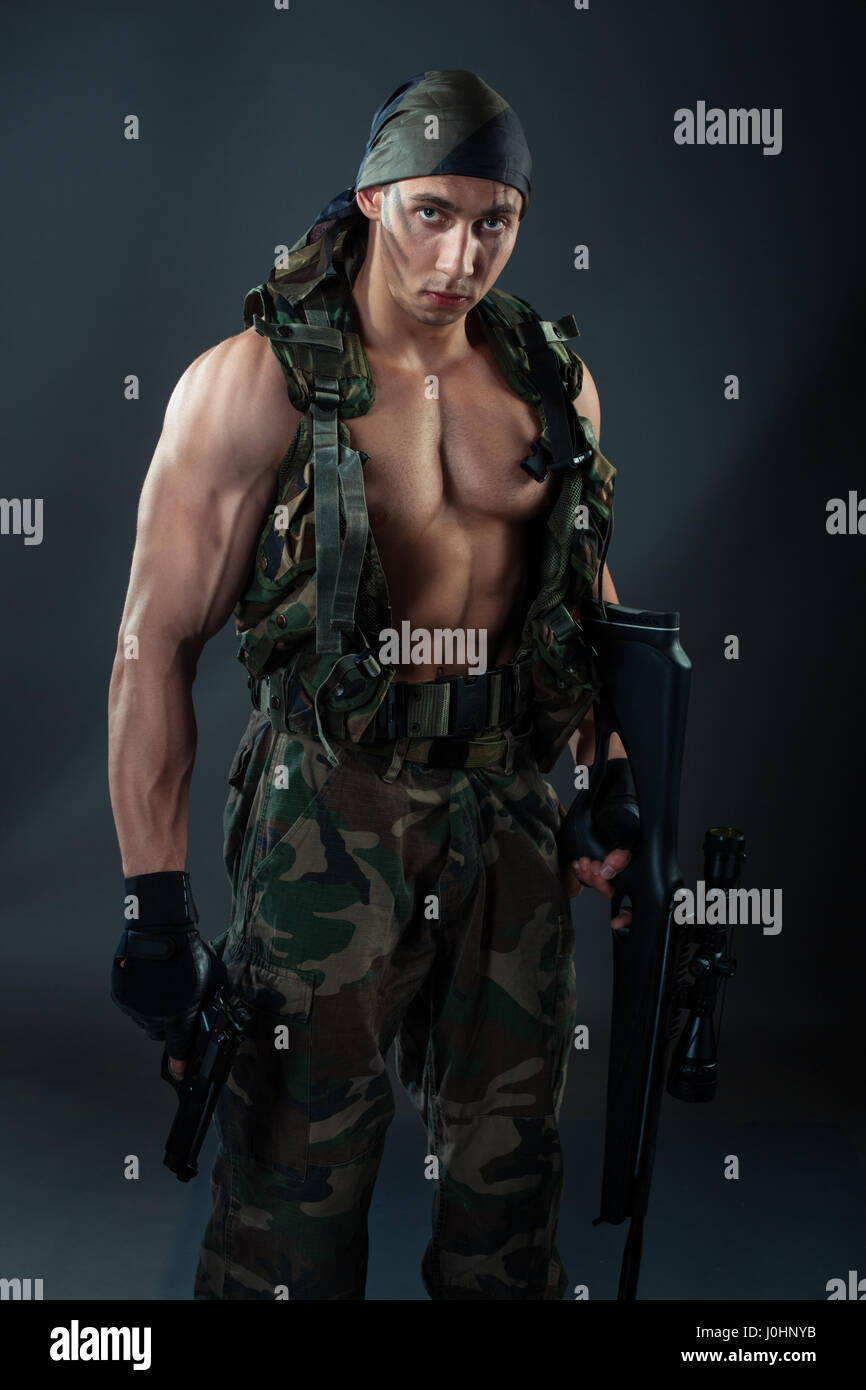 Military man in khaki uniforms. In his hands he holds a rifle and a ...