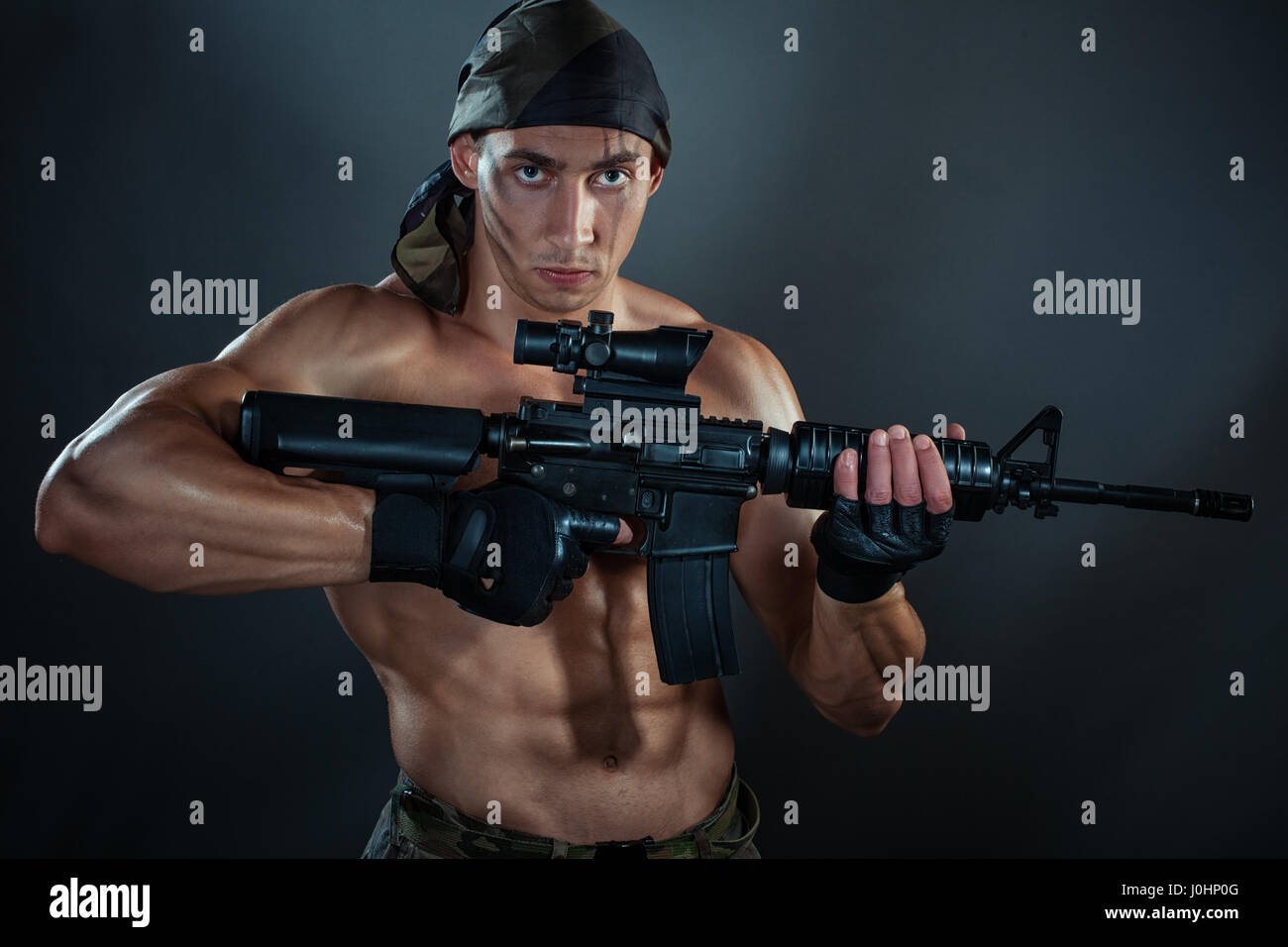Military man. He is holding an automatic weapon. He has big muscles ...