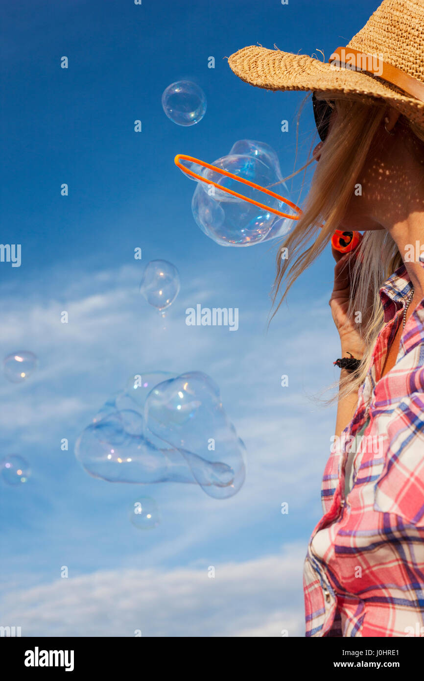 Young woman wearing straw hat making soap bubbels Stock Photo - Alamy