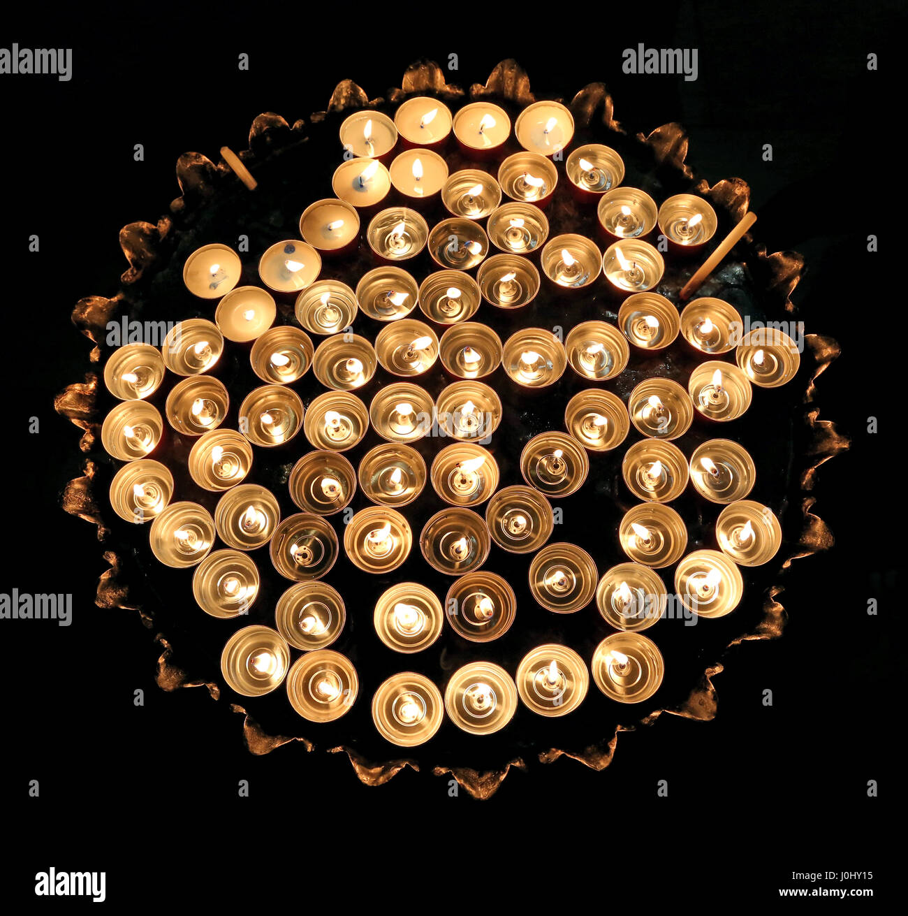 many candles lit with the warm flame during the religious ceremony ...