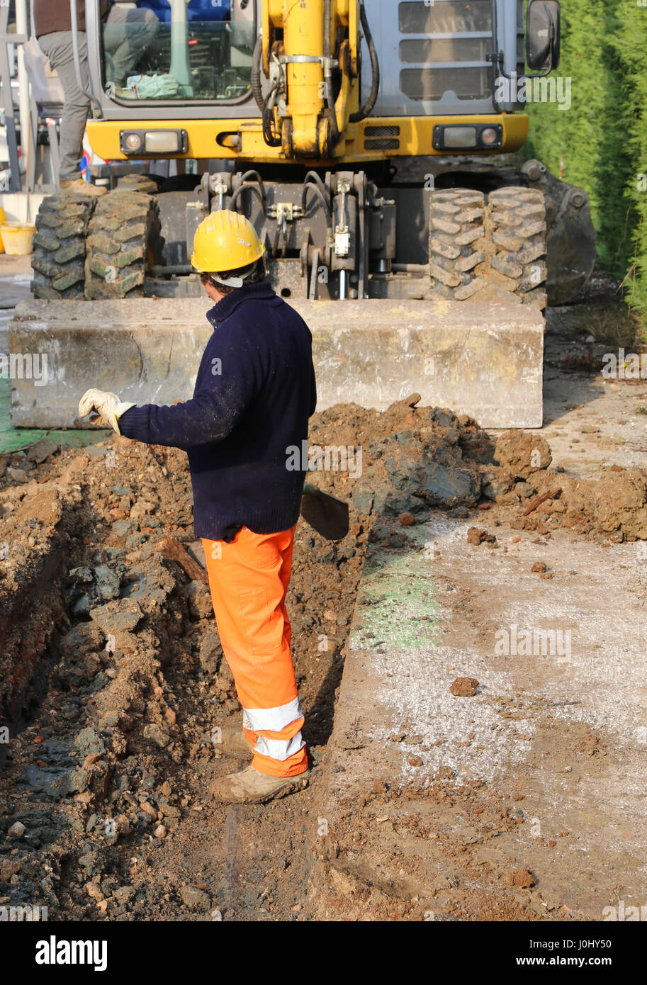 man at work inside the trench and the big bulldozer in the roadwork ...