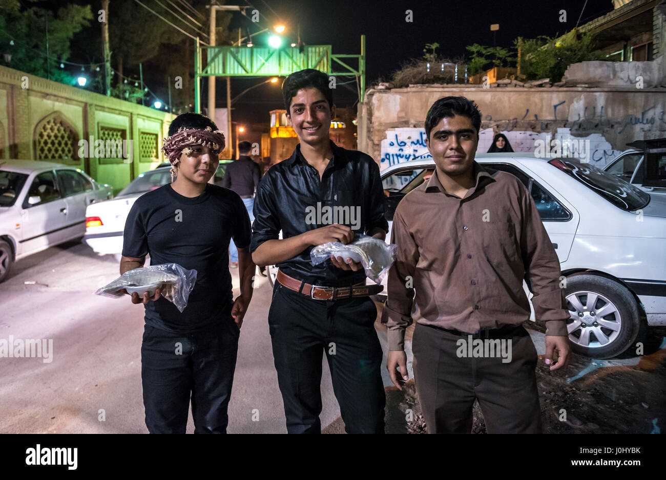 Young Iranians pose with nazri charity food served in during Muharram ...