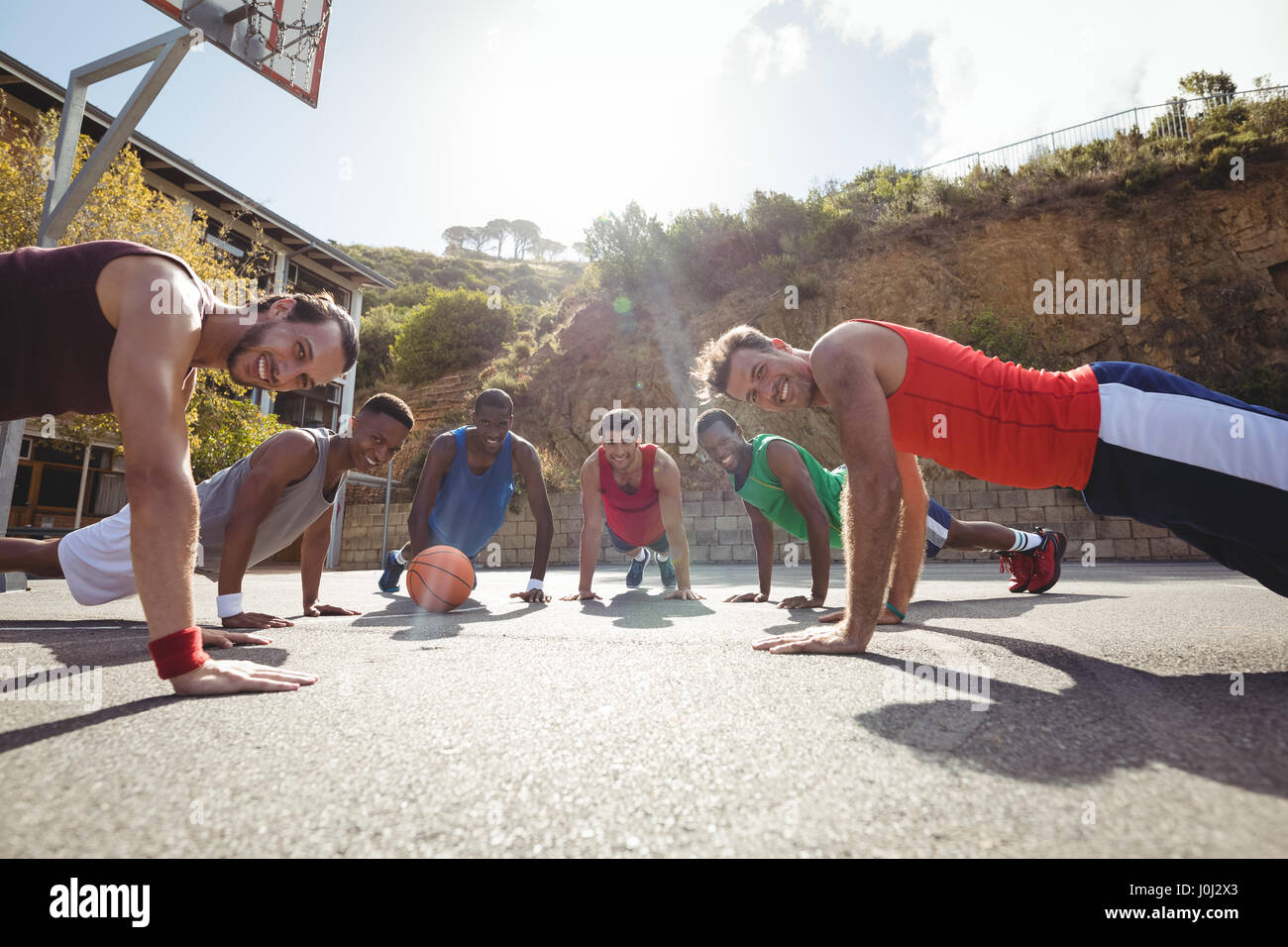 Basketball players performing push up exercise in basketball court ...