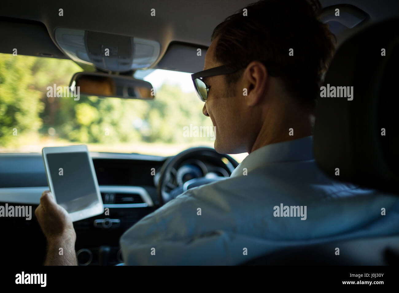 Rear view of man using digital tablet in car Stock Photo - Alamy