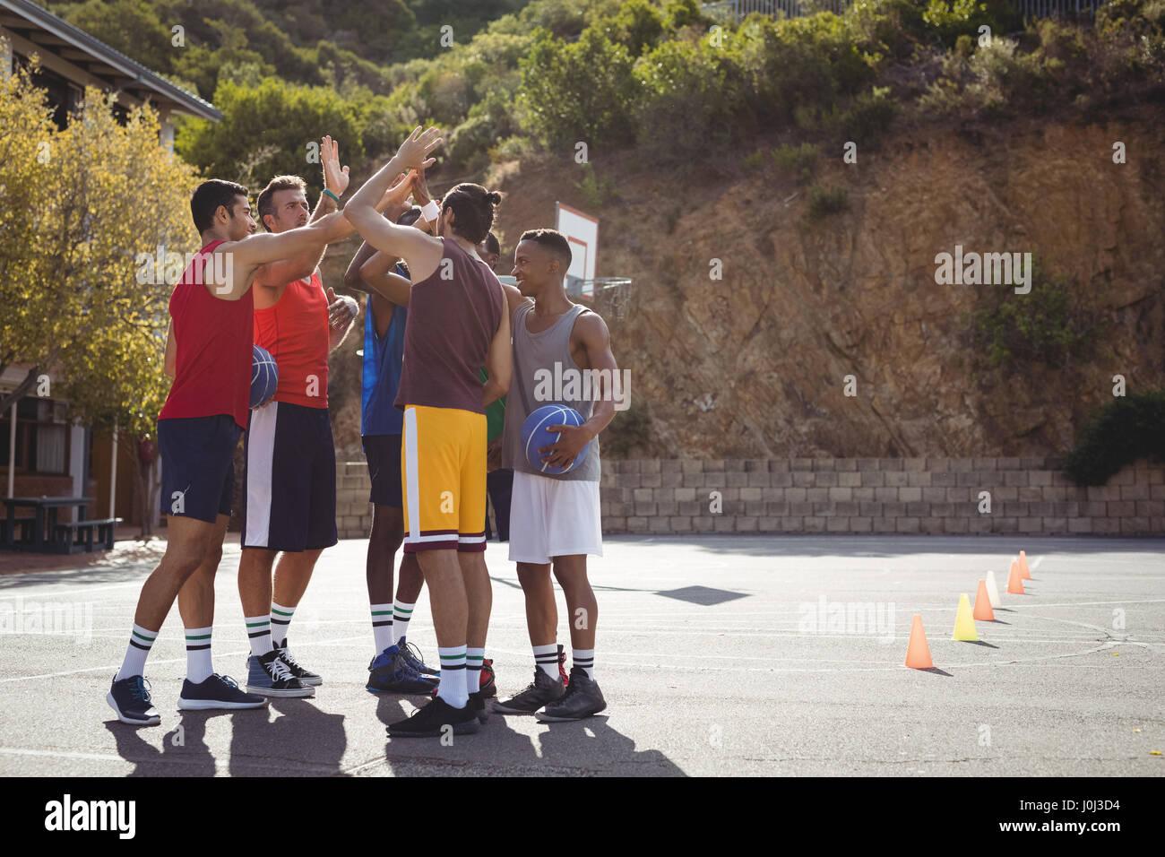 Basketball players giving high five to each other in basketball court ...