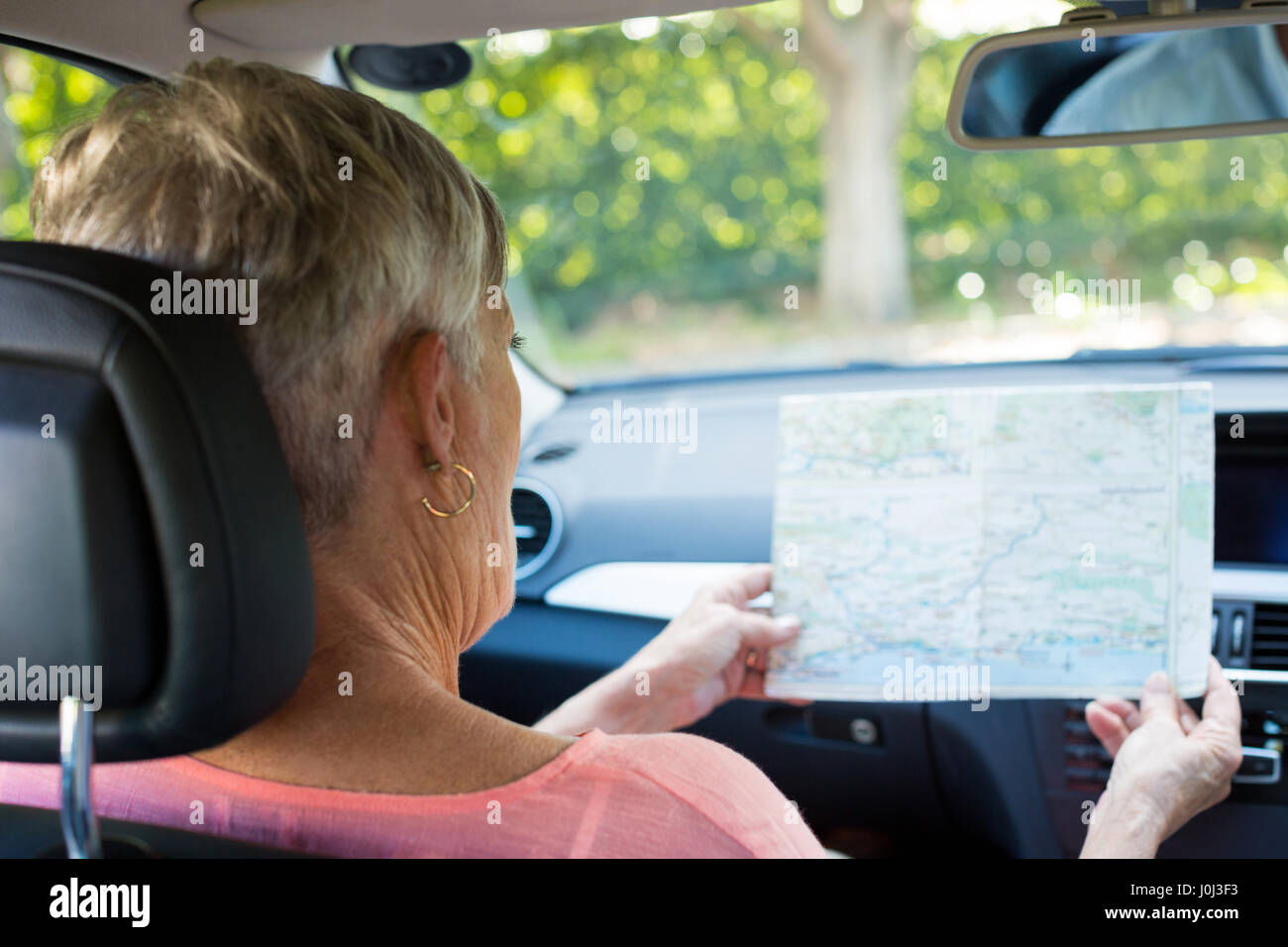 Rear view of senior woman reading map while sitting in car Stock Photo ...