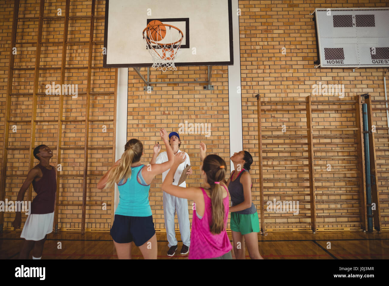 Coach helping high school team to score a goal while playing basketball ...