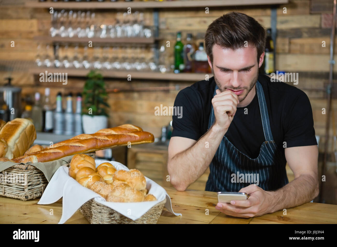Waiter using mobile phone at counter in cafÃƒÂ© Stock Photo - Alamy