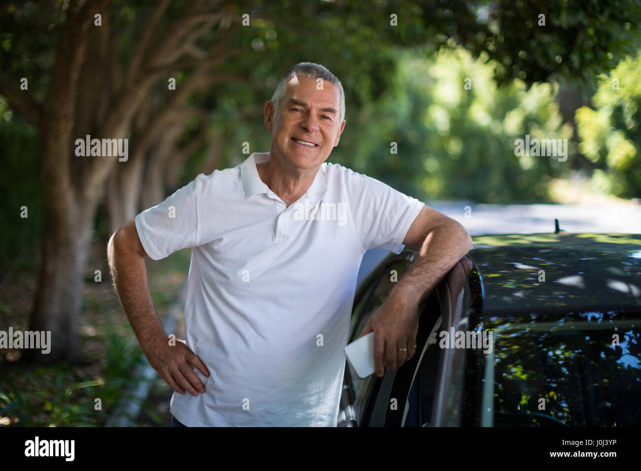 Portrait of smiling senior man standing by car Stock Photo - Alamy