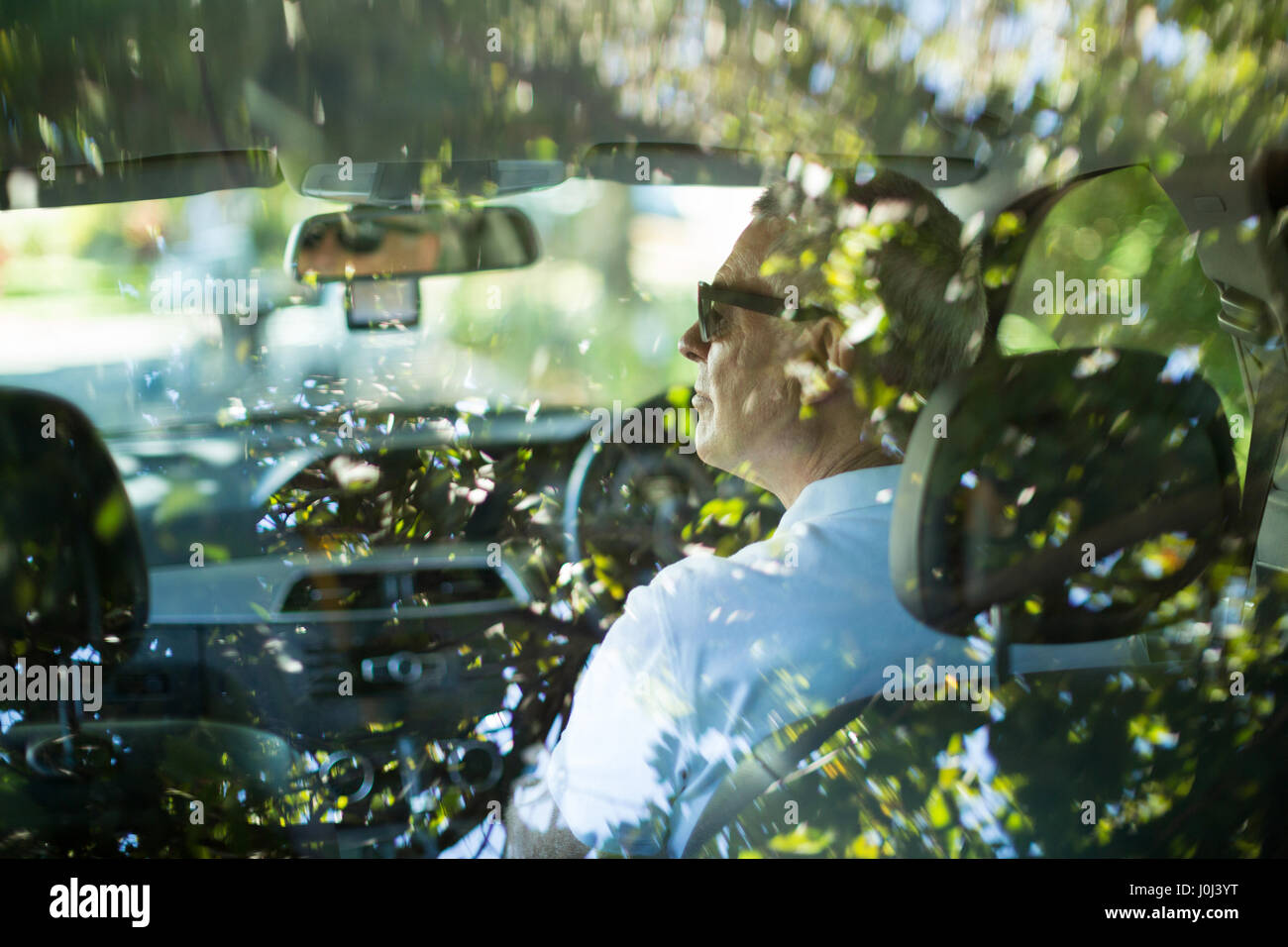 Rear view of senior man driving car seen through rear windshield Stock ...