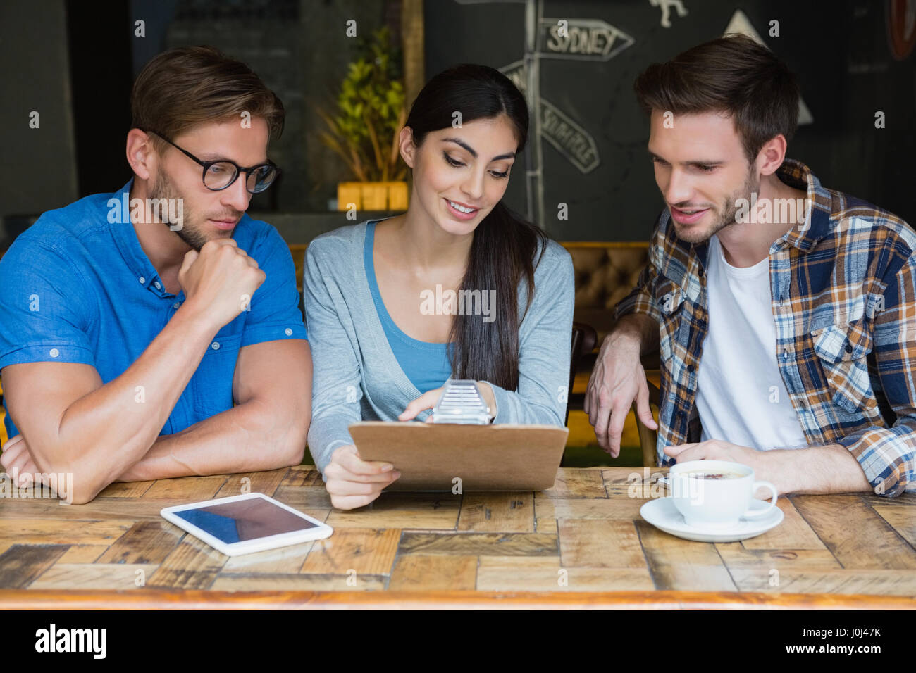 Friends discussing over clipboard while having coffee in cafÃƒÂ© Stock ...