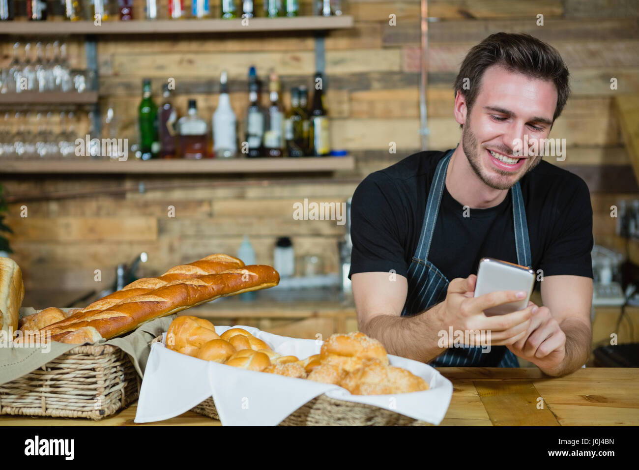 Waiter using mobile phone at counter in cafÃƒÂ© Stock Photo - Alamy