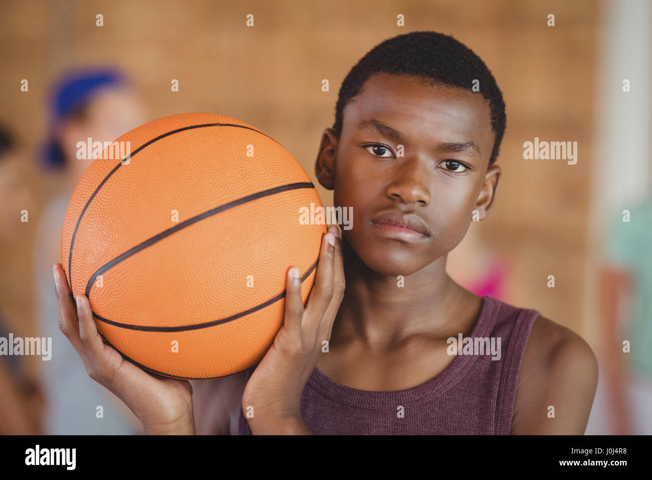 Determined high school boy standing with basketball in the court Stock ...