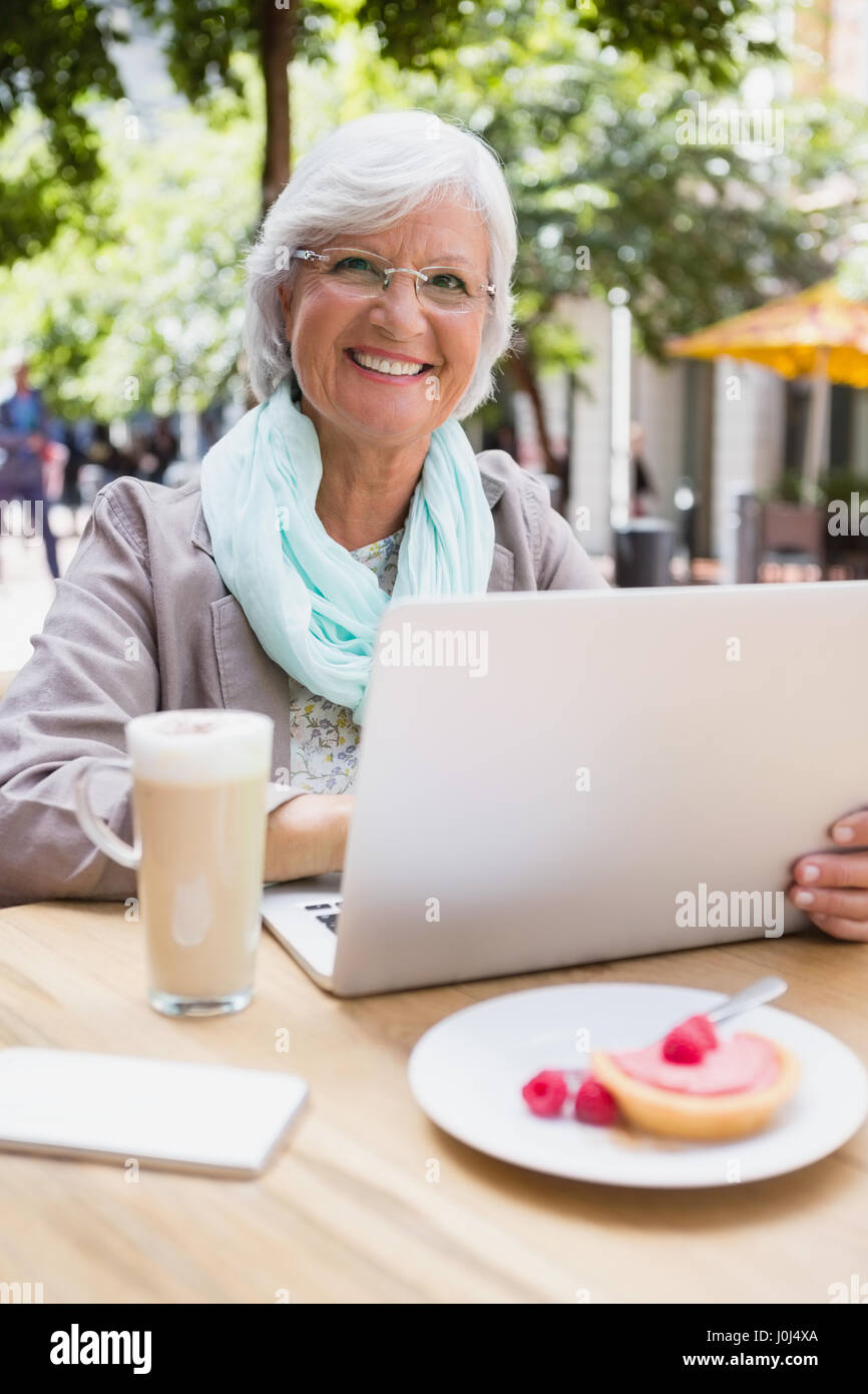 Smiling senior woman using laptop in outdoor cafÃƒÂ© Stock Photo - Alamy