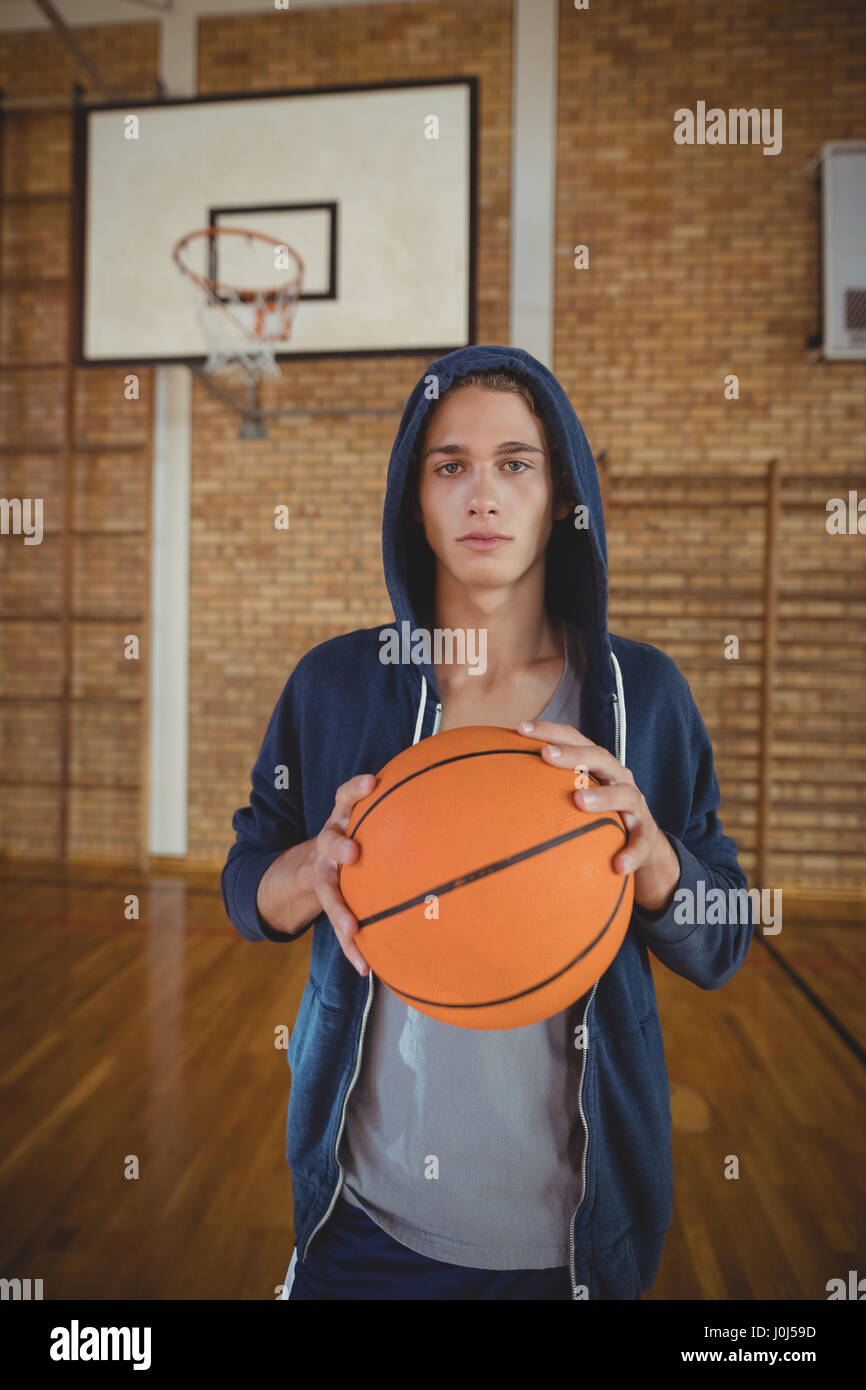 Determined high school boy standing with basketball in the court Stock ...