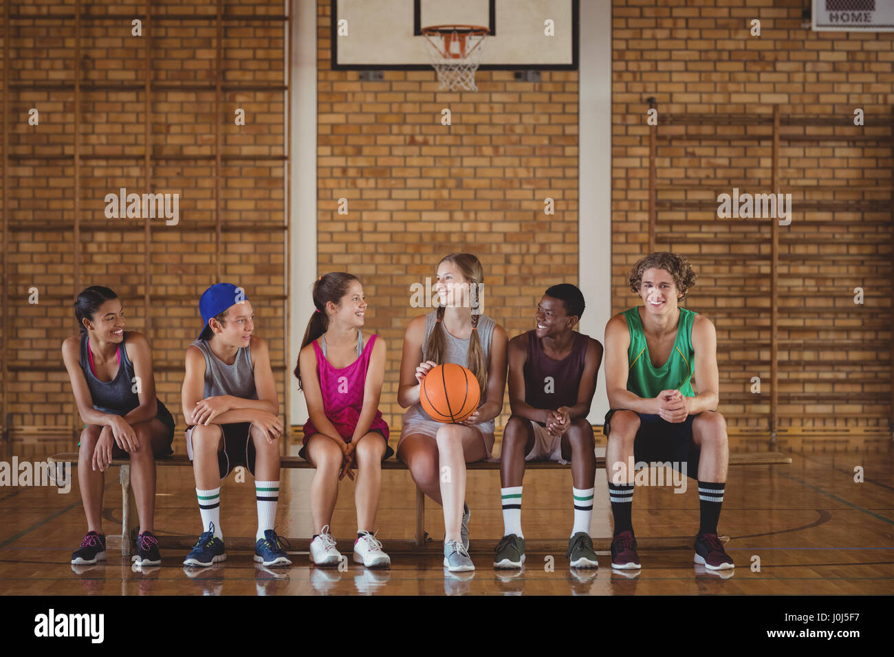 High school kids sitting on a bench in basketball court indoors Stock ...