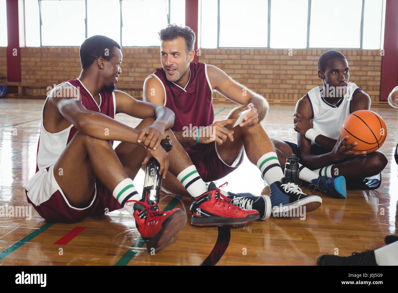 Smiling basketball players interacting while relaxing in the court ...