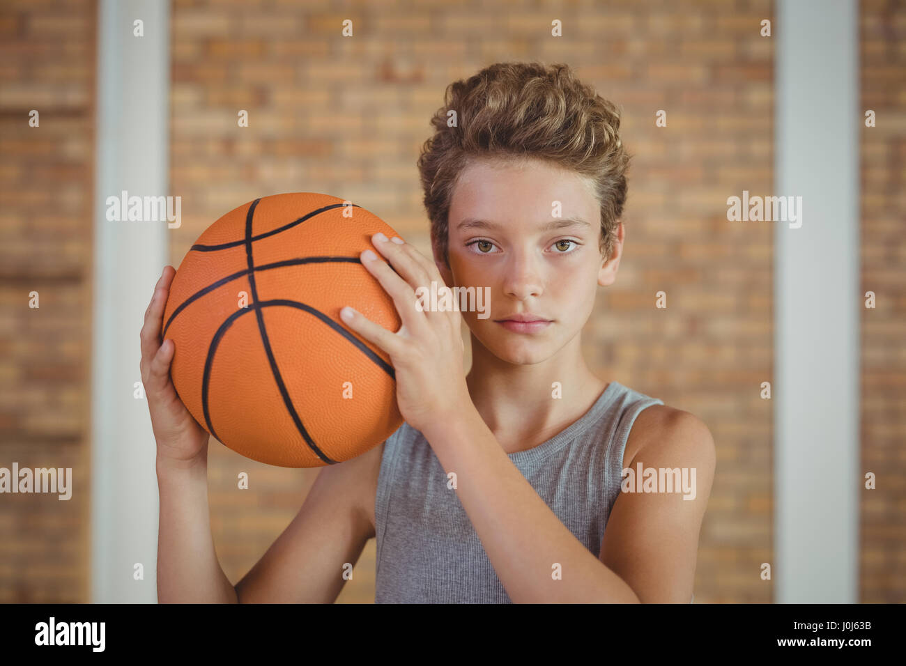 Determined boy holding a basketball in the court Stock Photo - Alamy