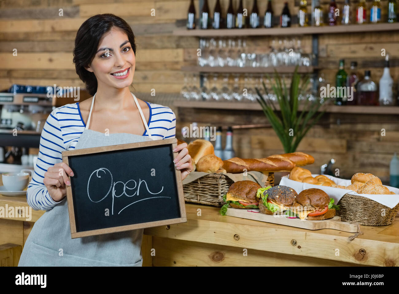 Portrait of waitress holding open signboard at counter in cafÃƒÂ© Stock ...
