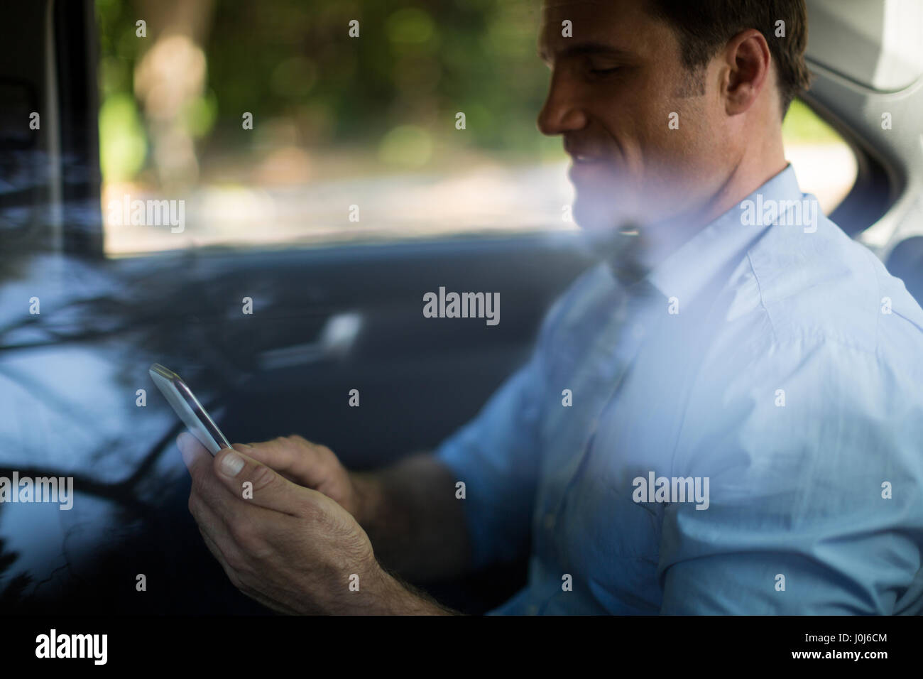 Man using mobile phone on back seat in car Stock Photo - Alamy
