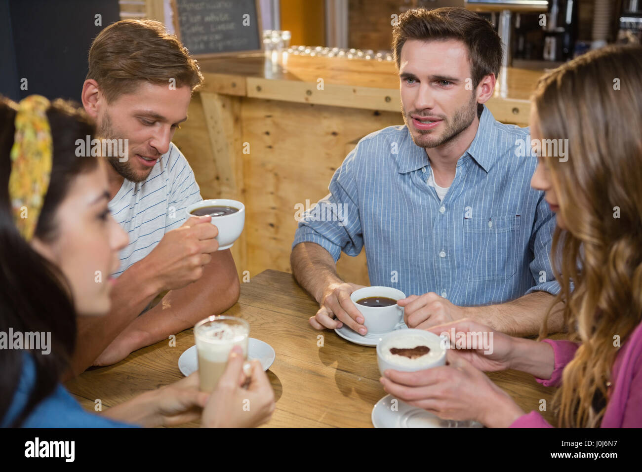 Friends interacting while having coffee at table in cafÃƒÂ© Stock Photo ...