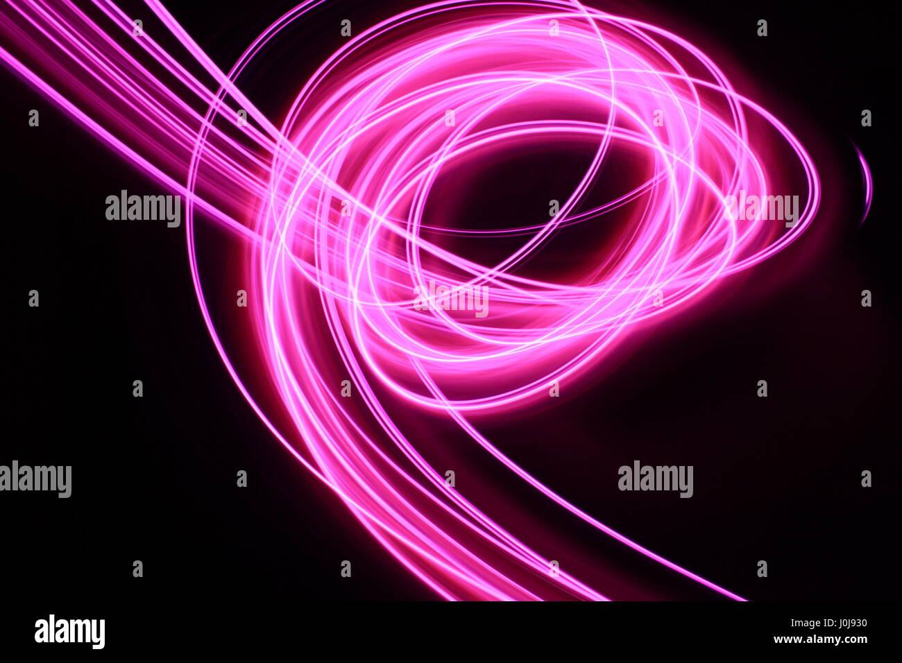 Pink light painting photography - loop and swirl on black background ...