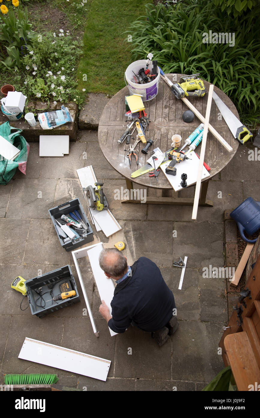 An overview of a handyman engaged in some DIY work on the garden patio ...
